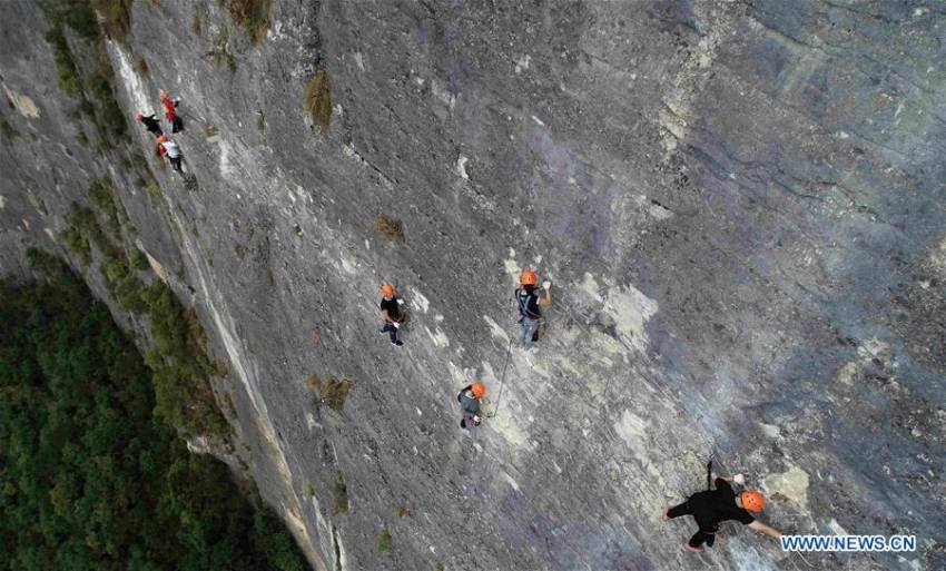 Sports fans climb rockface at Feilada Rock Climbing Base, China's Hubei